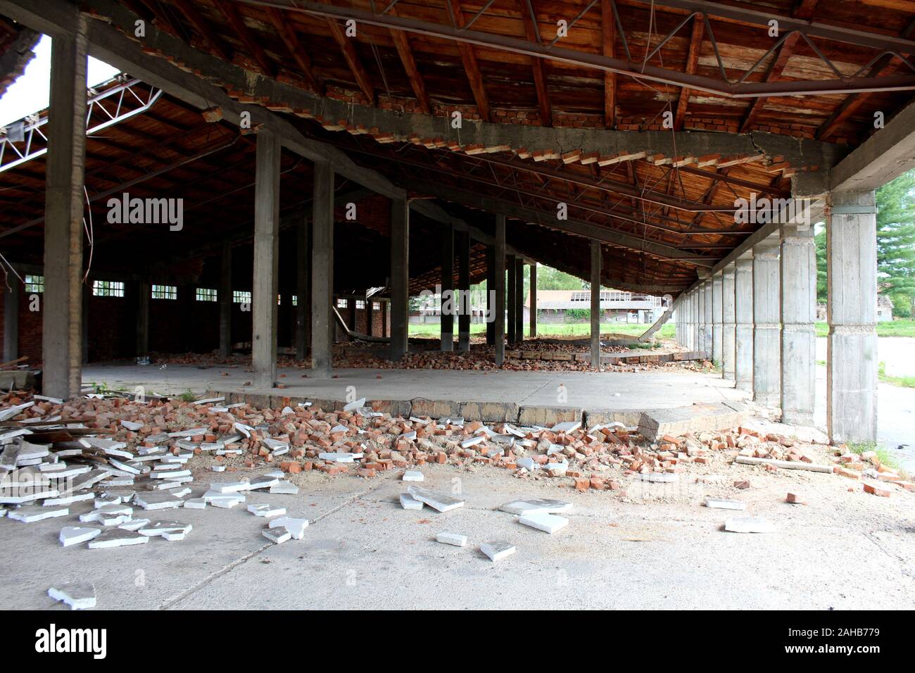 Inside of wide large hangar building with missing destroyed red brick ...