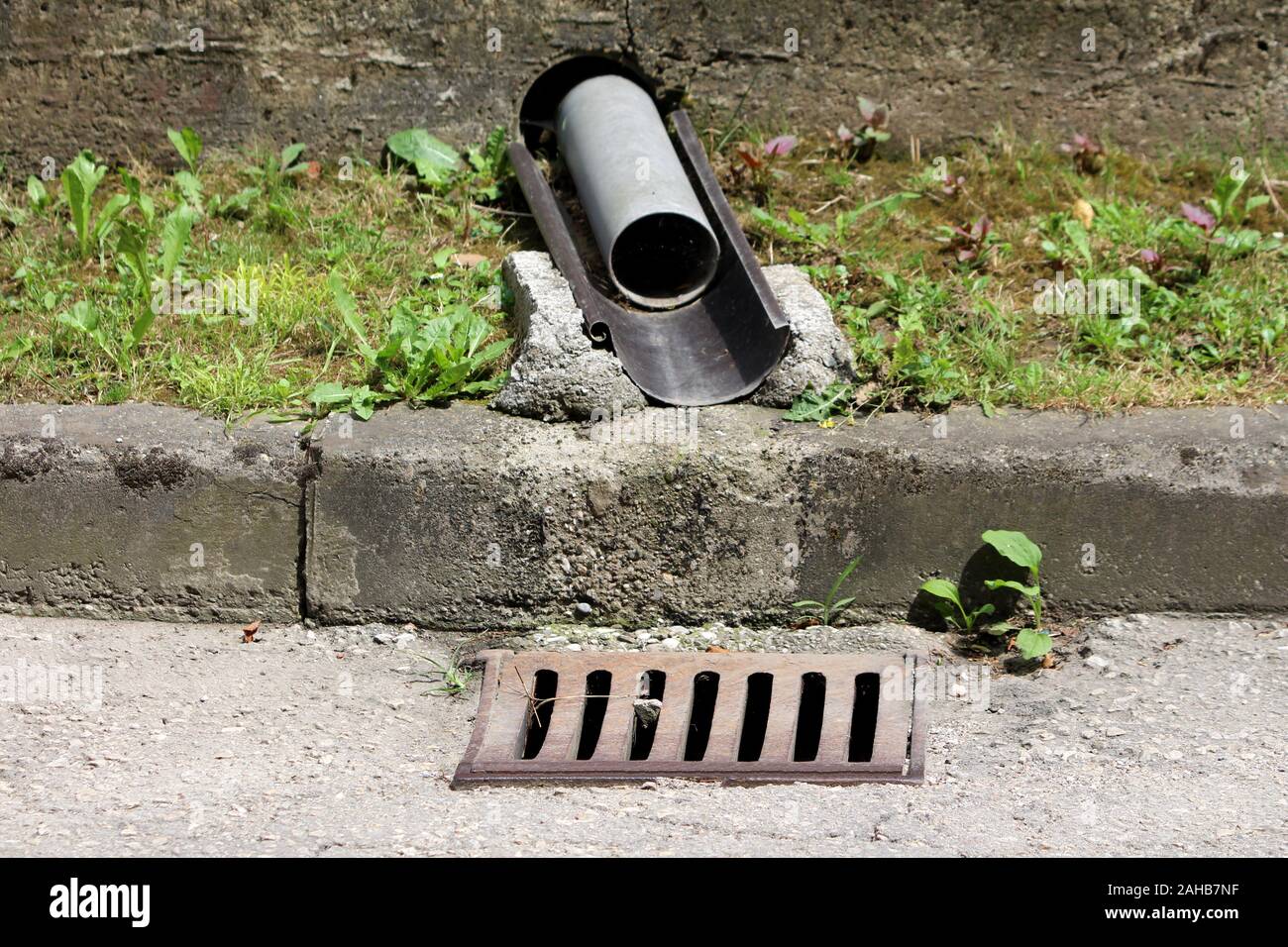 Makeshift plastic pipe and metal gutter surrounded with concrete and ...