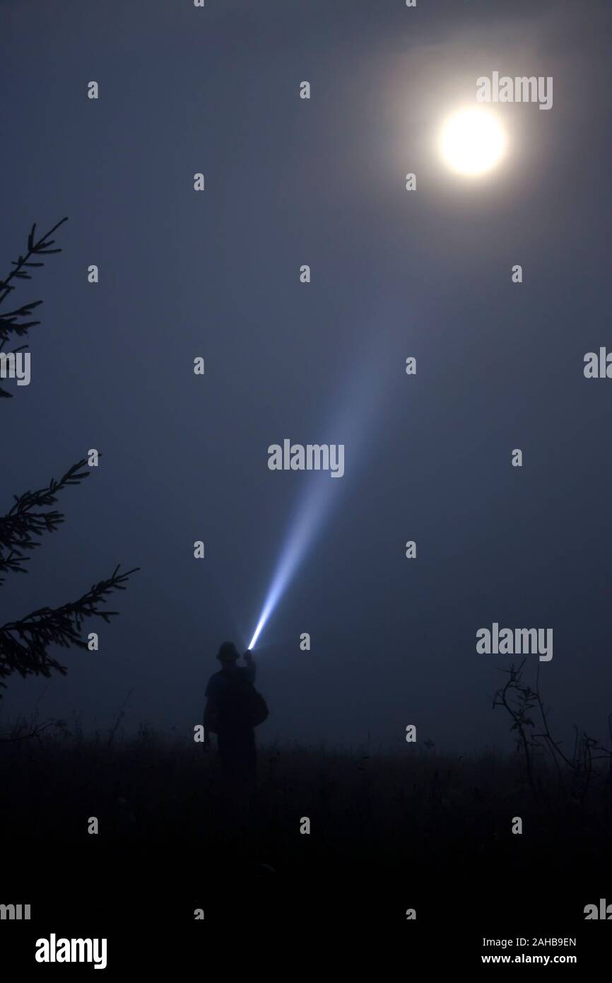 Man shines a flashlight in the night moon sky Stock Photo - Alamy