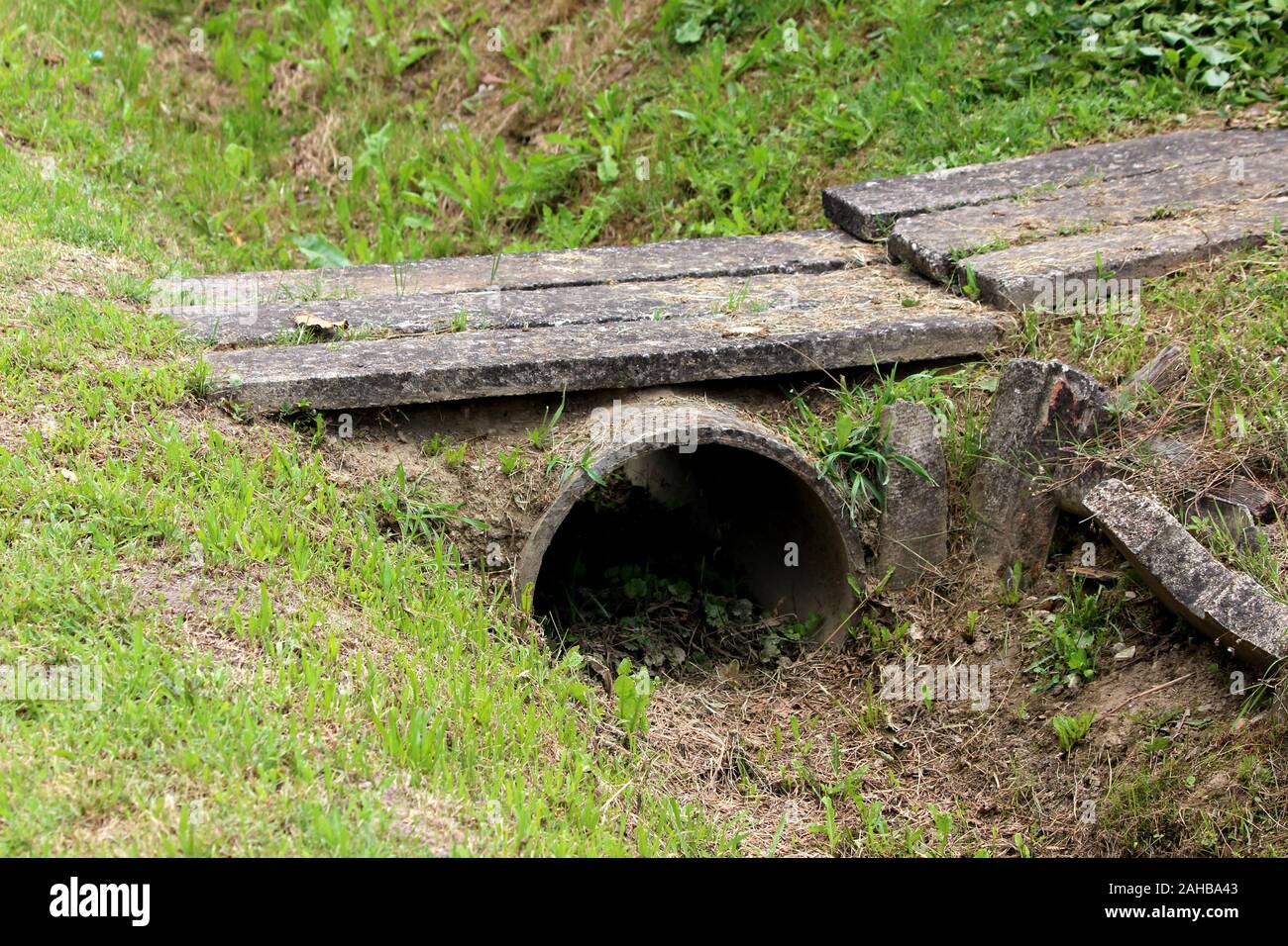 Storm drain concrete pipe covered with old dilapidated concrete tiles ...