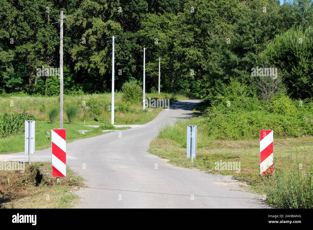 Vertical red and white striped caution warning road signs at slight ...