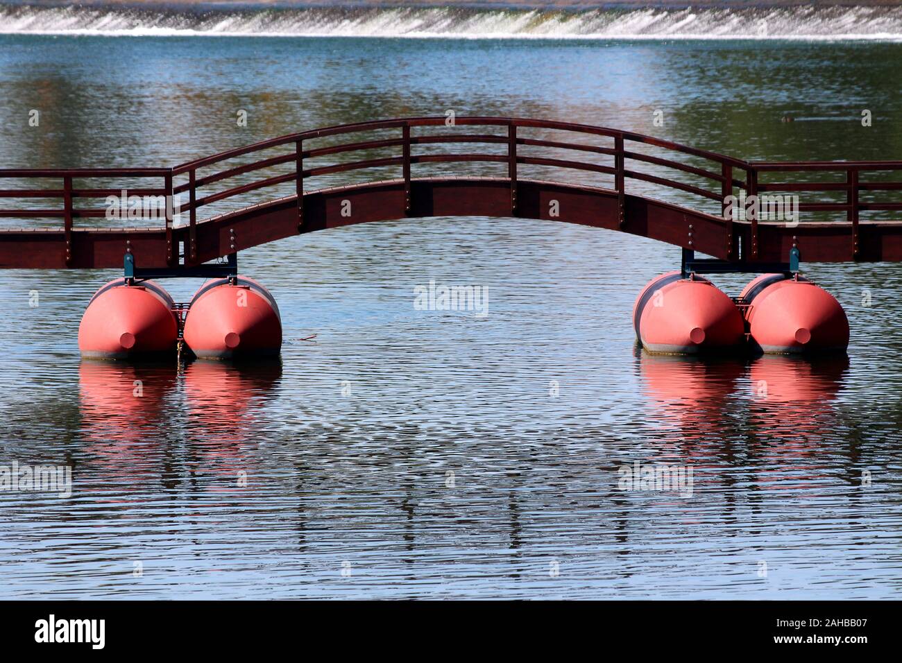 Wooden floating pontoon bridge with red floats and center arch secured ...