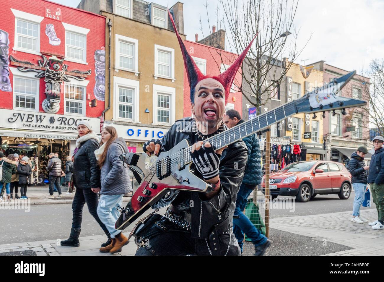 Man dressed in Punk Rocker clothes with spiked hair and a guitar poses ...