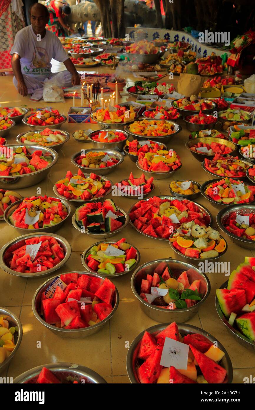 Priest sits beside arrays of offerings placed under the ancient banyan ...