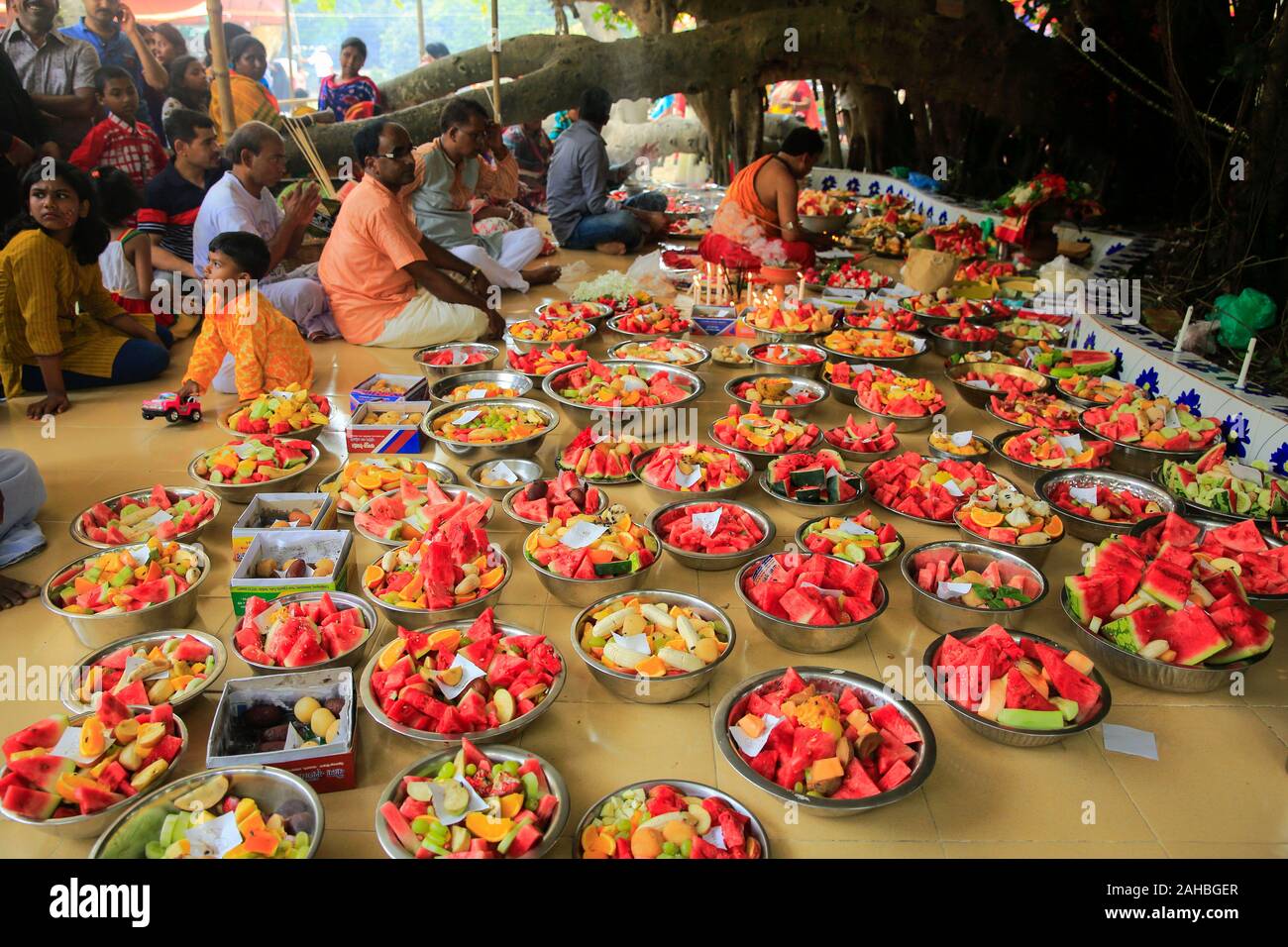Priest sits beside arrays of offerings placed under the ancient banyan ...