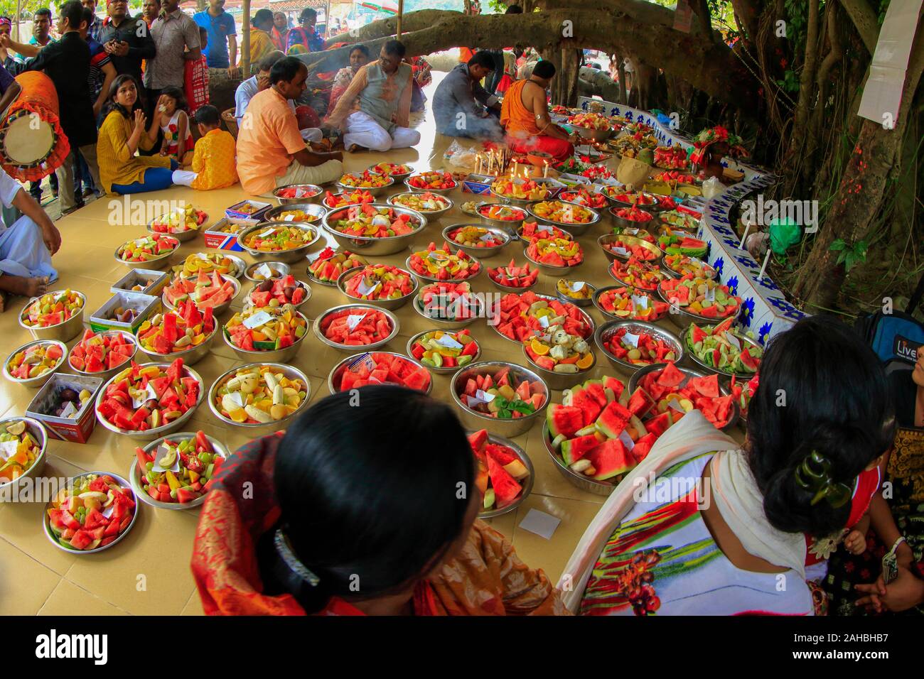 Priest sits beside arrays of offerings placed under the ancient banyan ...