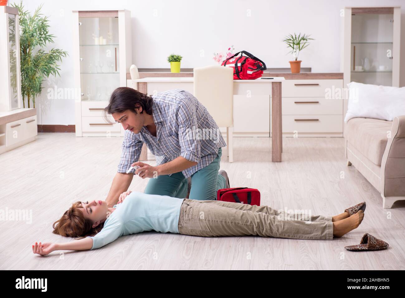 The young couple in first aid concept at home Stock Photo - Alamy