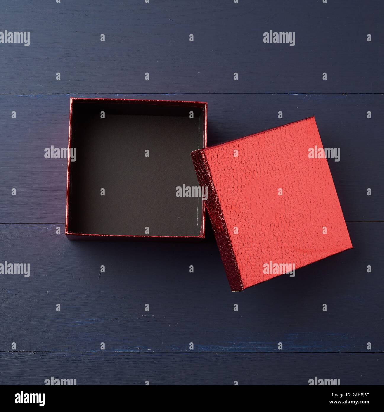 open empty red square cardboard box on a dark blue wooden background ...