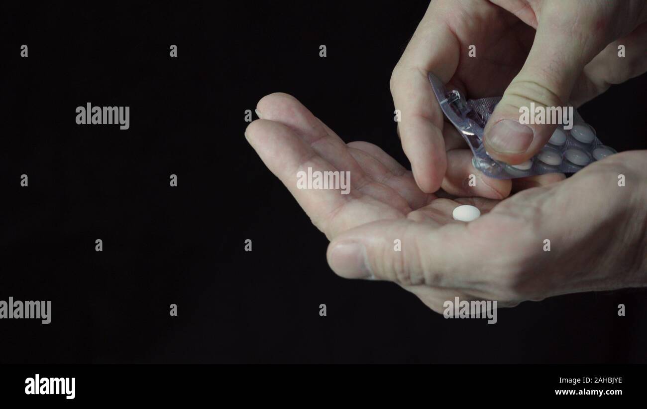 The tablet falls into the hand. A man receives medicine from a package ...