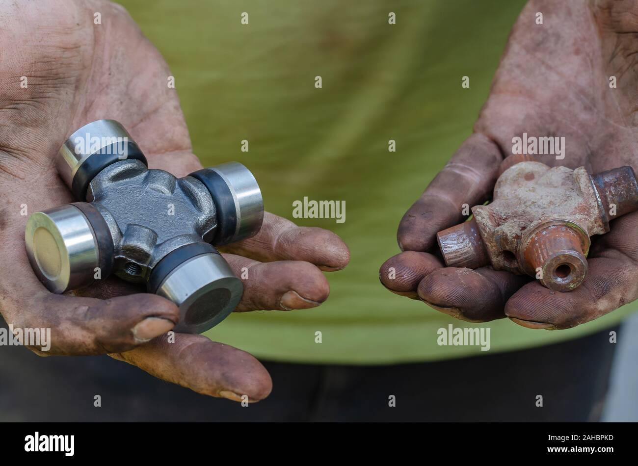 The car mechanic is holding in his hands an old with a new cross of the ...