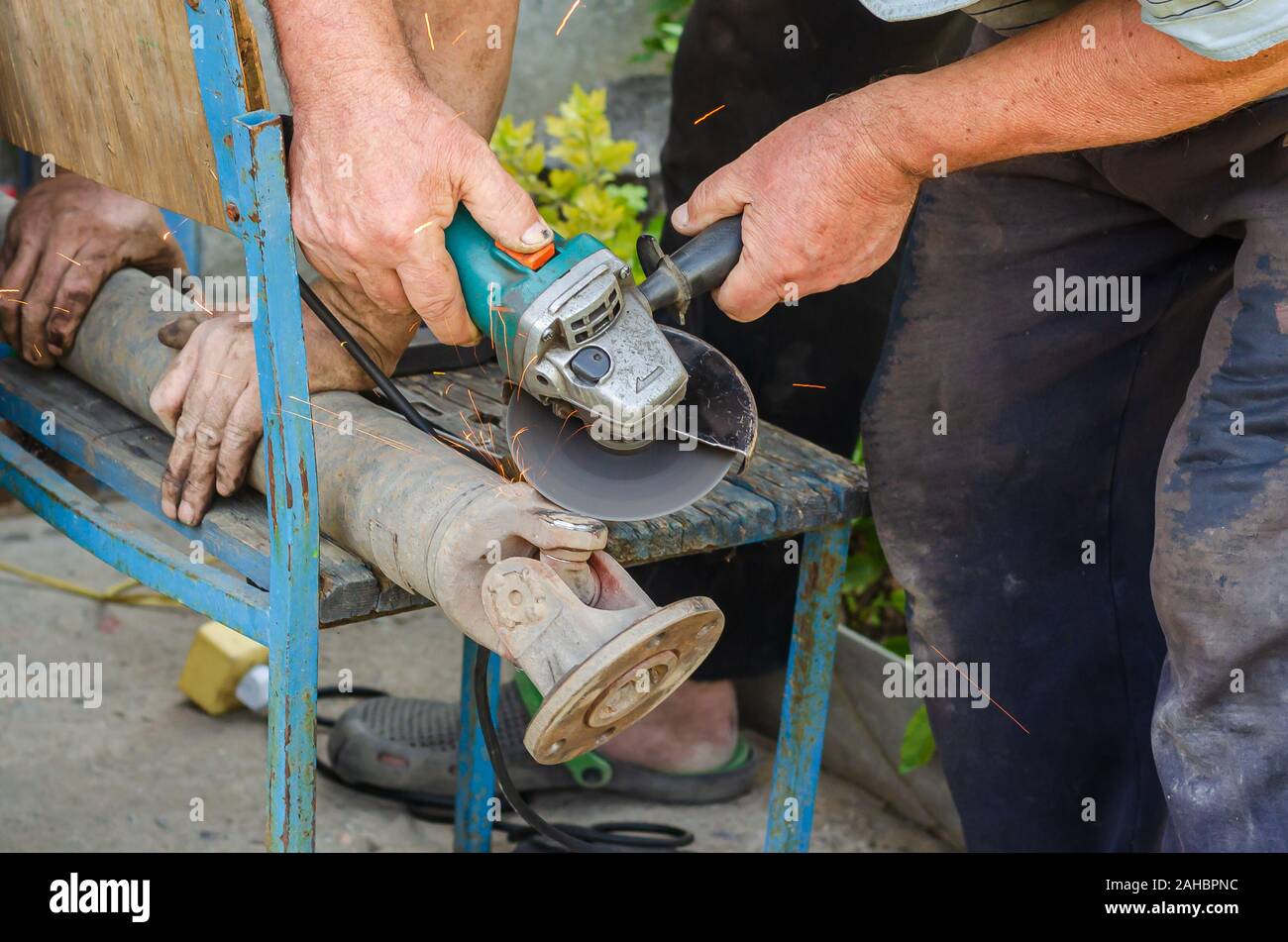 Two men with the help of the grinder disassemble the crosses of the ...