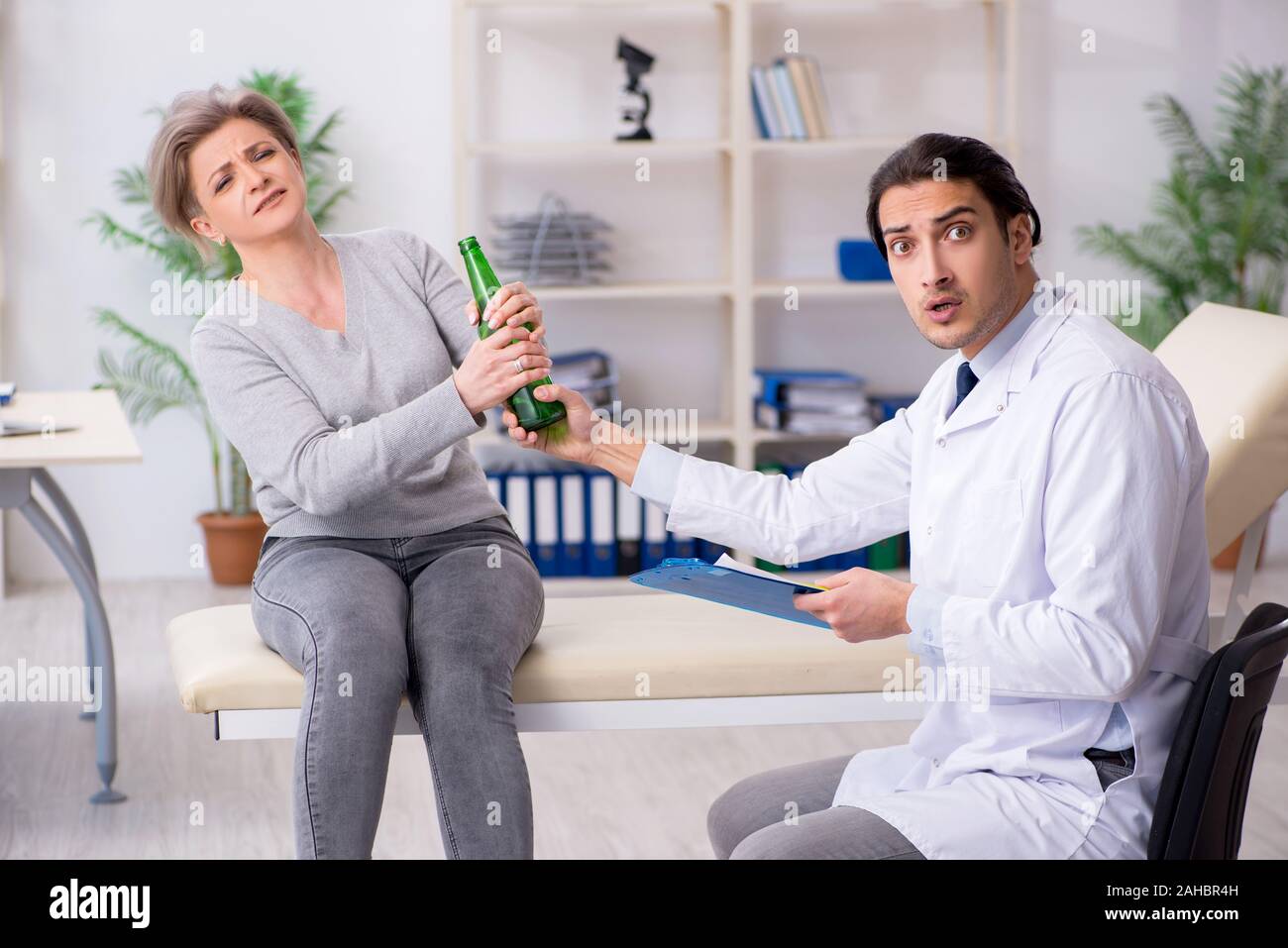 The female alcoholic visiting young male doctor Stock Photo - Alamy