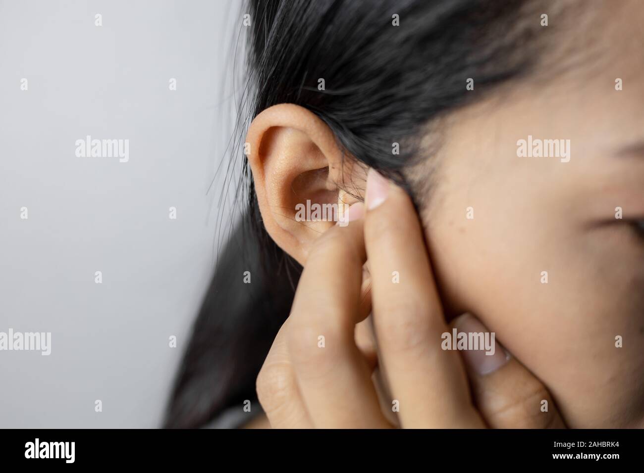 Young woman with of earache on a gray background. Asian woman is ...