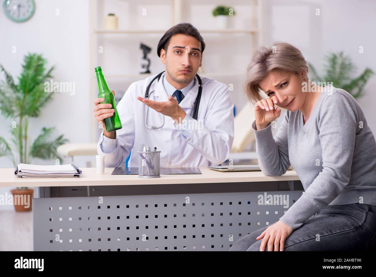 The female alcoholic visiting young male doctor Stock Photo - Alamy