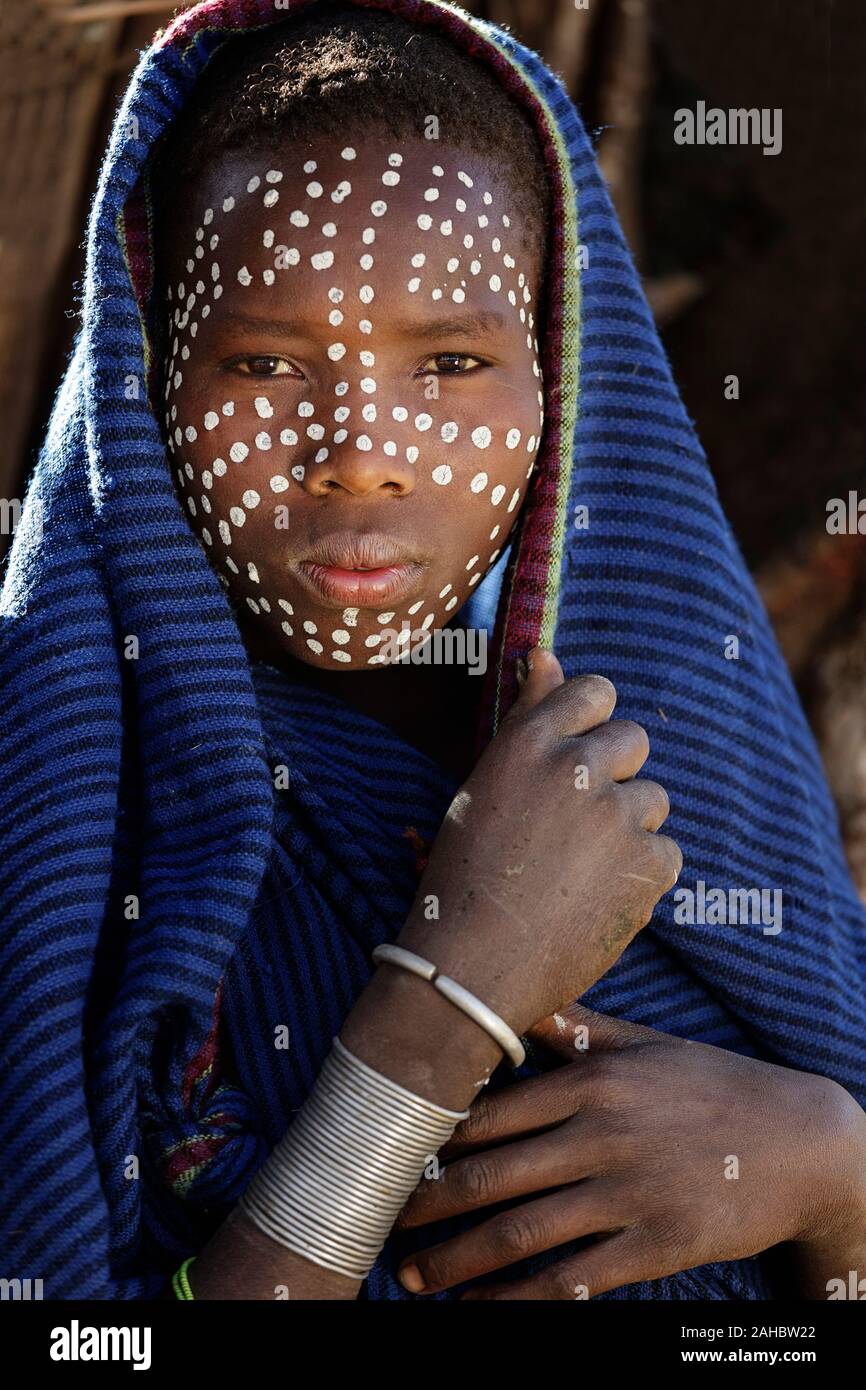 Girl with painted face holding blanket covering her head with her hand ...