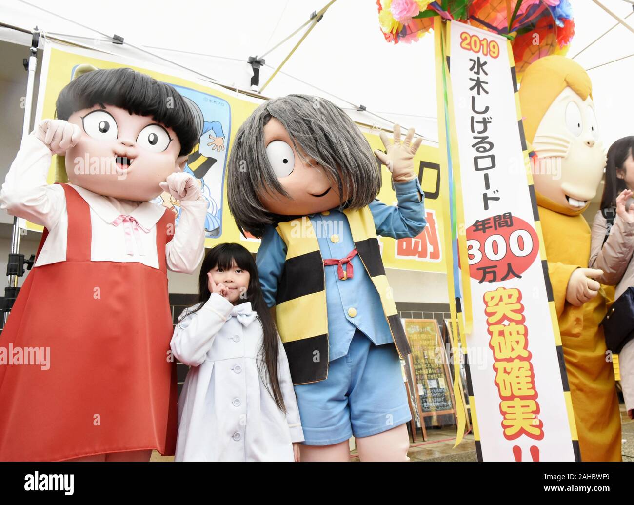 A girl poses for a photo together with mascots for characters from the ...
