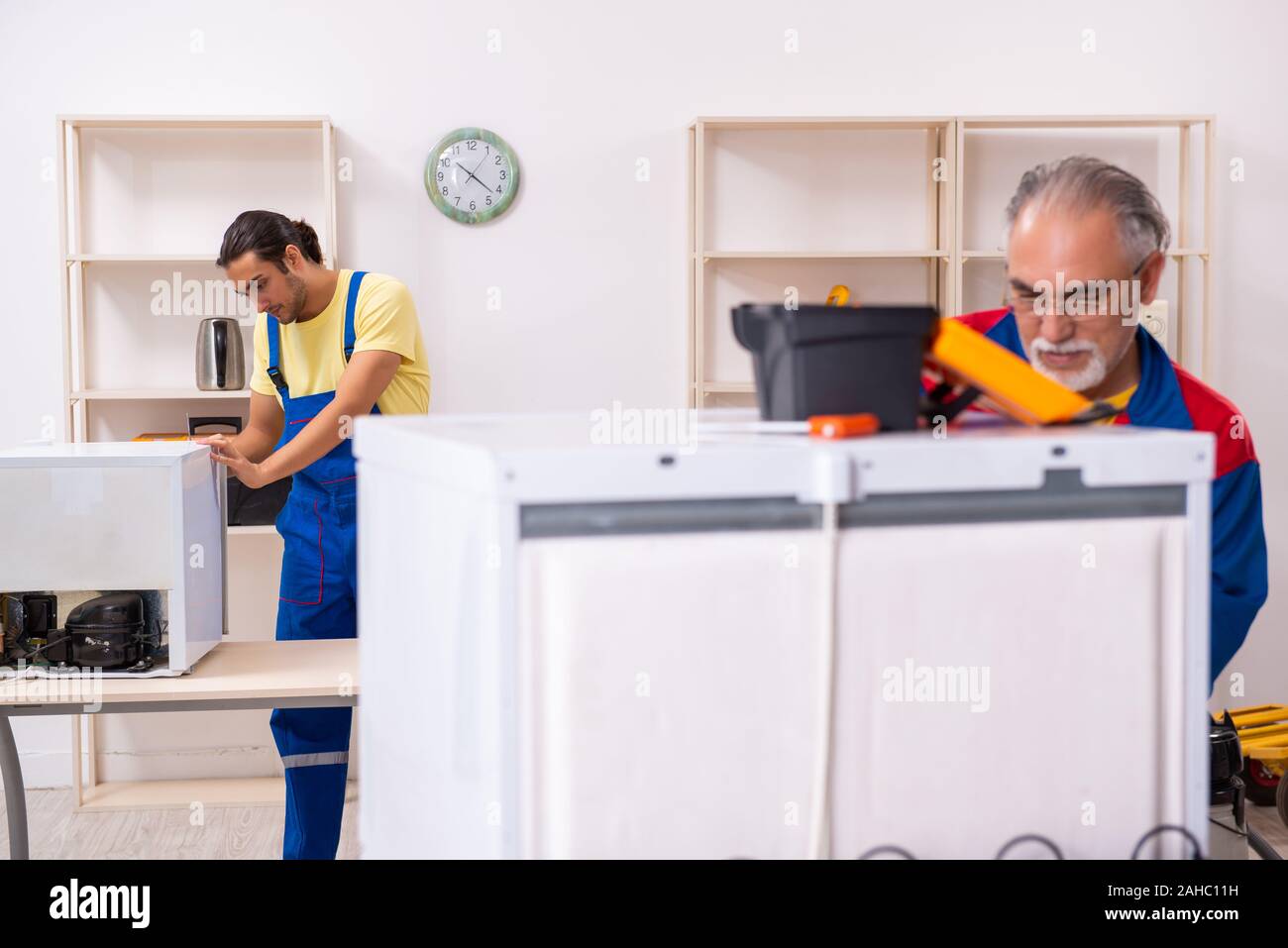 The two contractors repairing fridge at workshop Stock Photo - Alamy