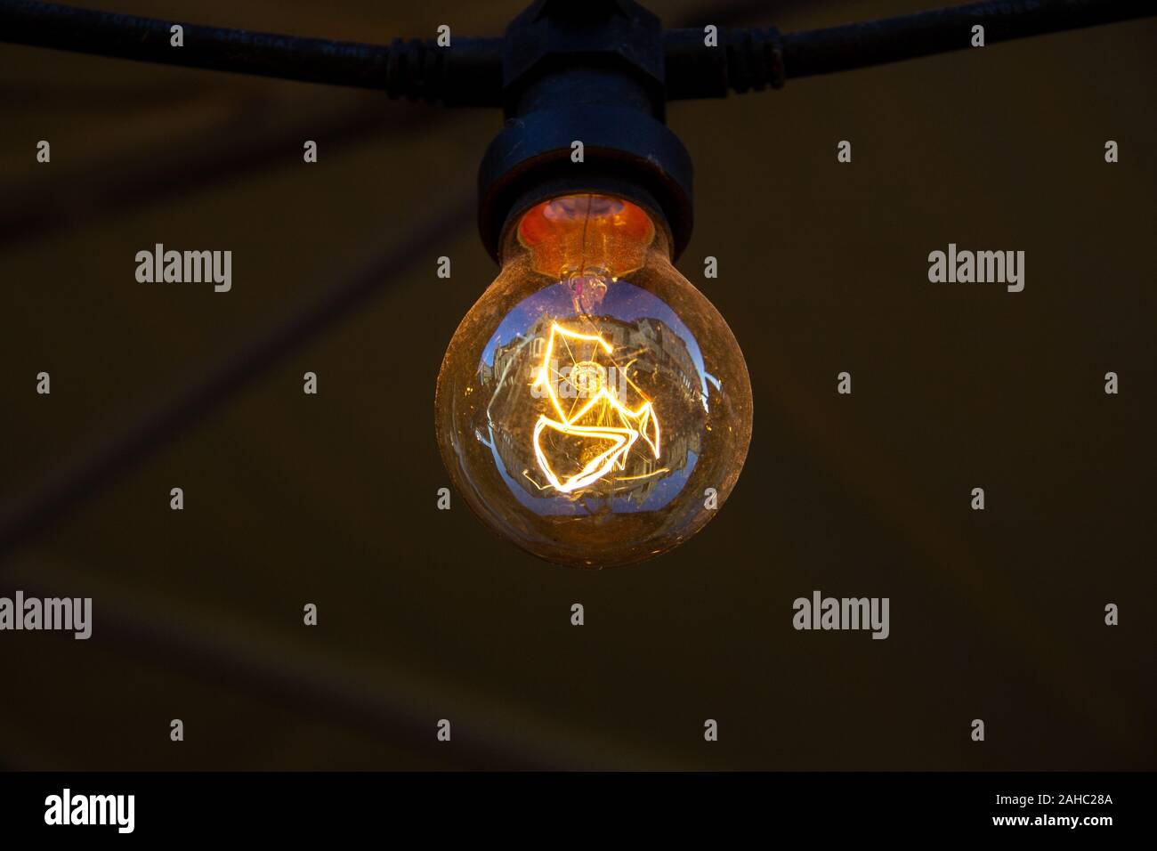 A single electric light bulb lit hanging from the ceiling Stock Photo ...