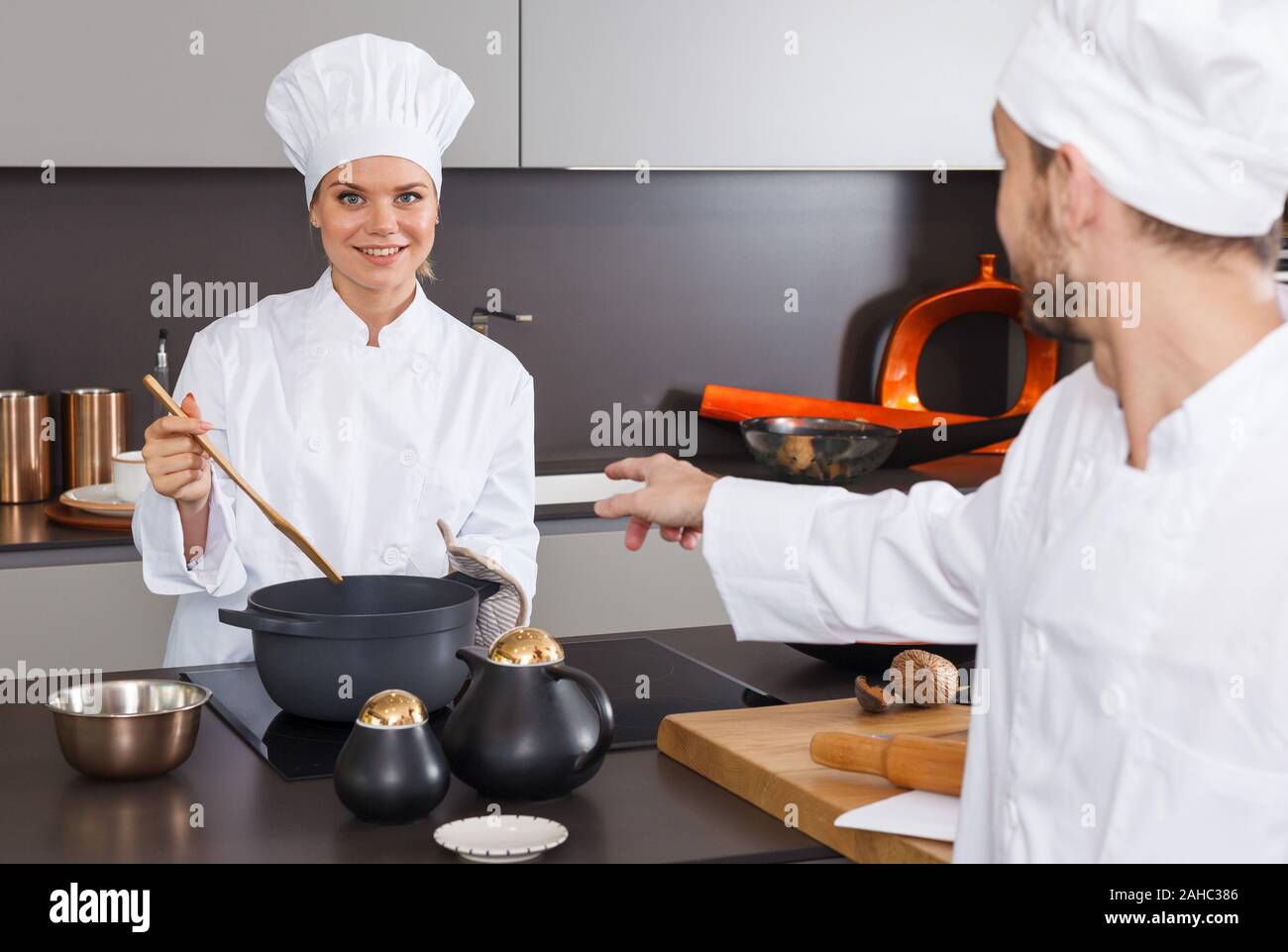 Young smiling woman chef cooking in modern interior of private kitchen ...