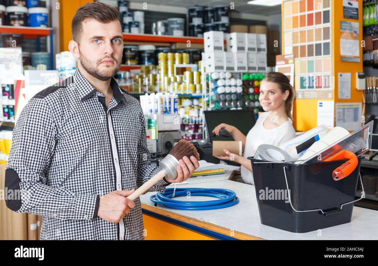 Man customer with tools and young woman seller at cash desk in tool ...
