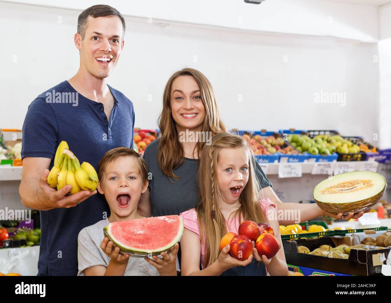 Positive family with children showing fresh delicious fruits in ...