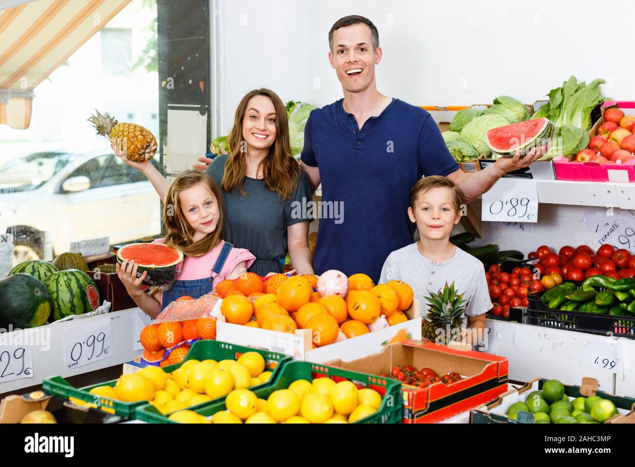 Smiling glad family with kids showing fresh delicious fruits during ...
