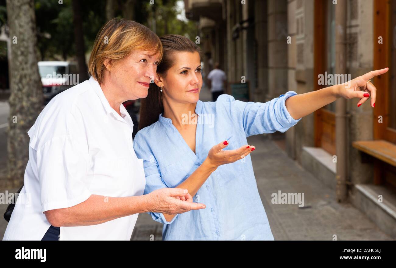 Friendly girl helping mature woman to find necessary address in city ...