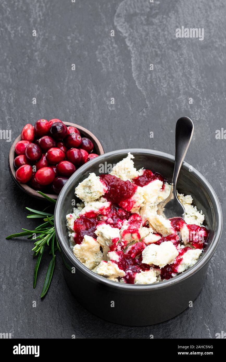 Potted aged Blue stilton cheese with cranberry sauce on black stone ...
