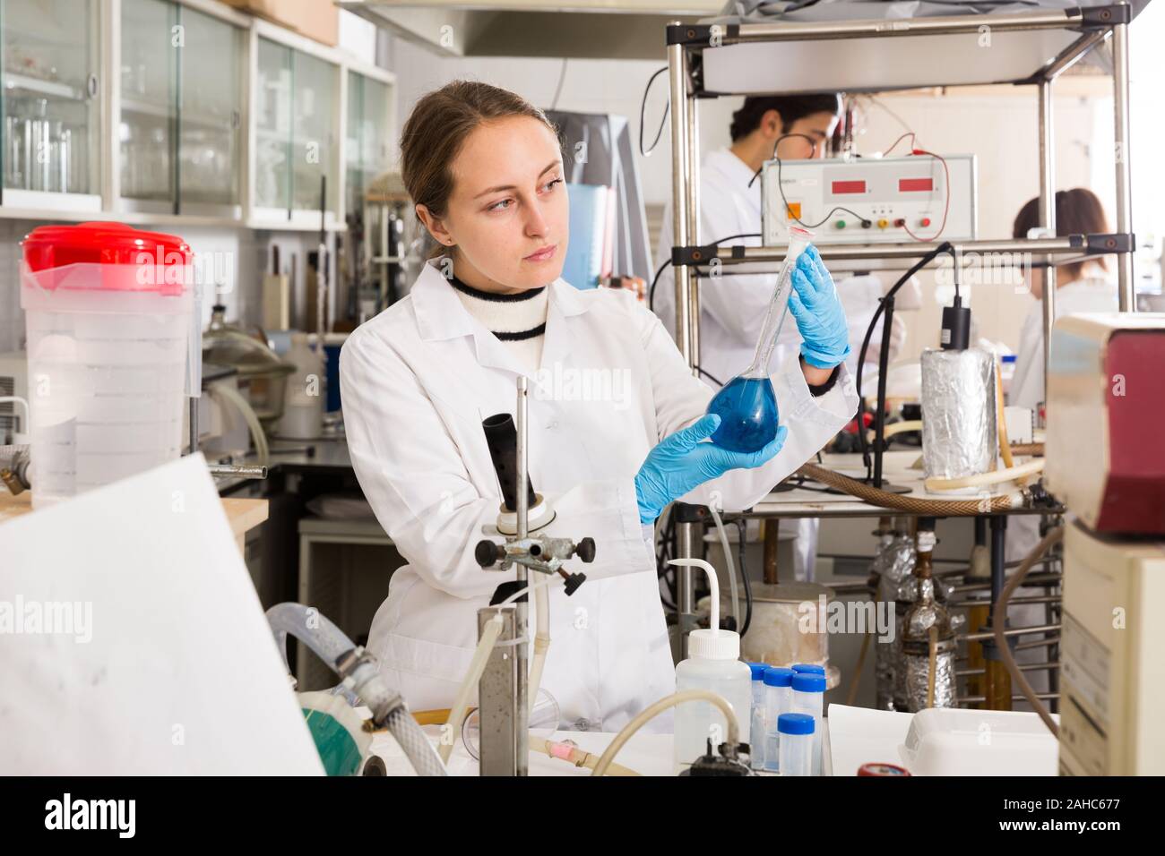Young female lab technician working with reagents in test tubes during ...