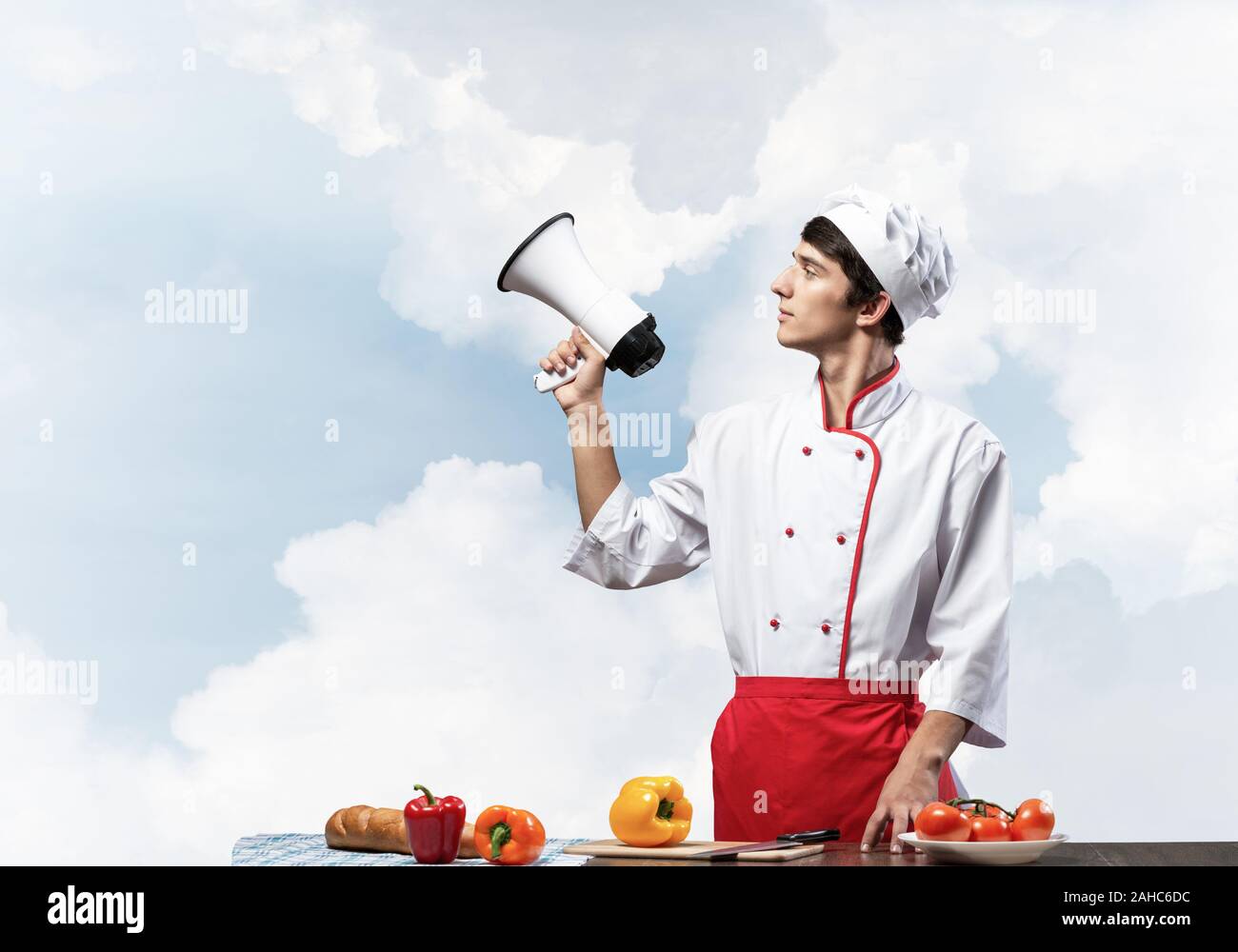 Young chef standing with megaphone in hand. Emotional caucasian chef in ...
