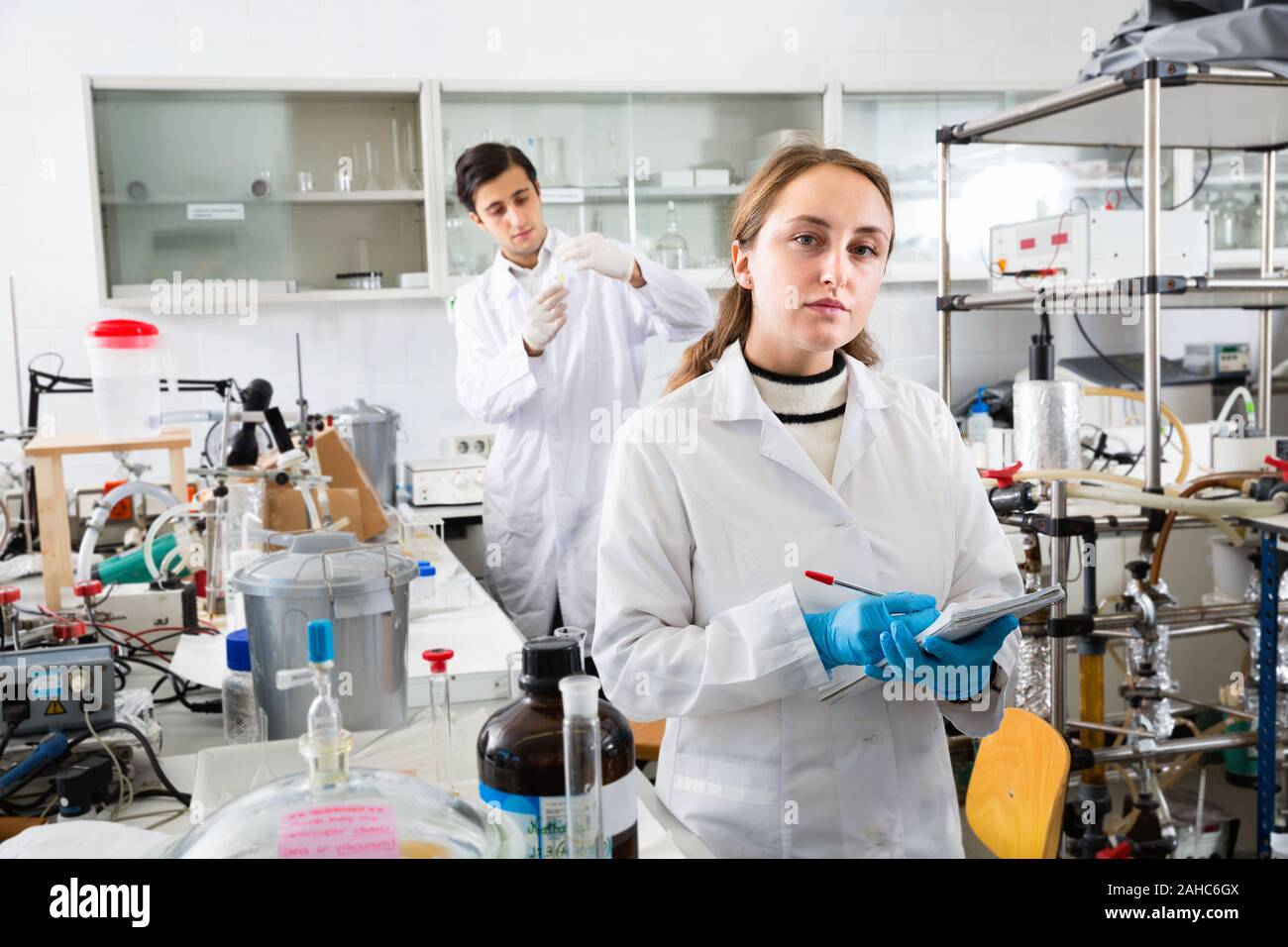 Portrait of young friendly woman lab technician writing report on ...