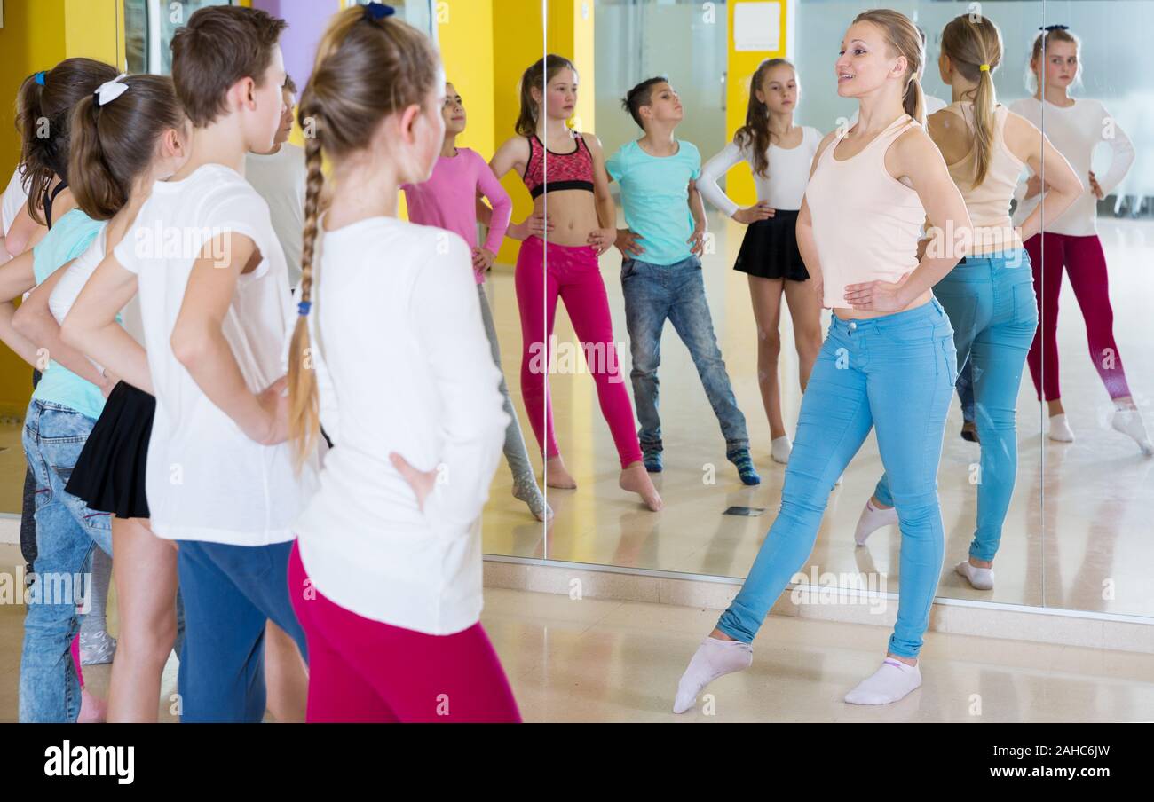 Young dance teacher giving children dance class, showing movements in ...