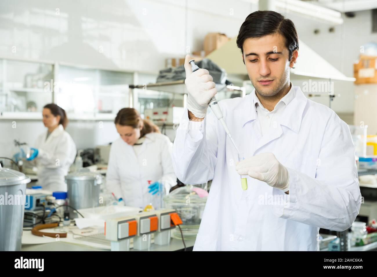 Scientific researching in laboratory. Focused young man pipetting ...