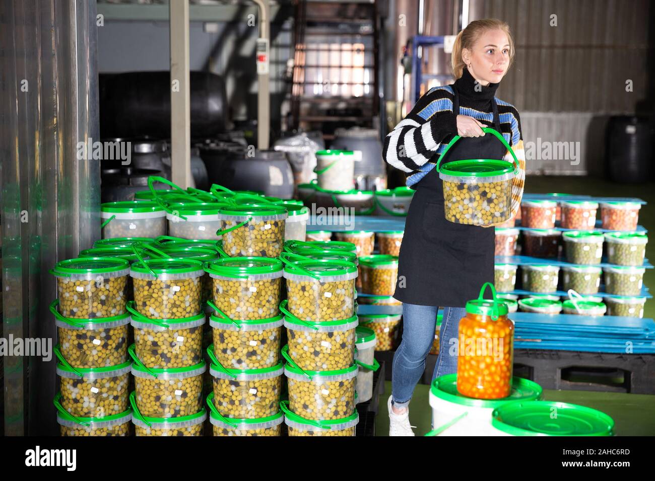 Positive woman working at the warehouse, stacking plastic containers ...