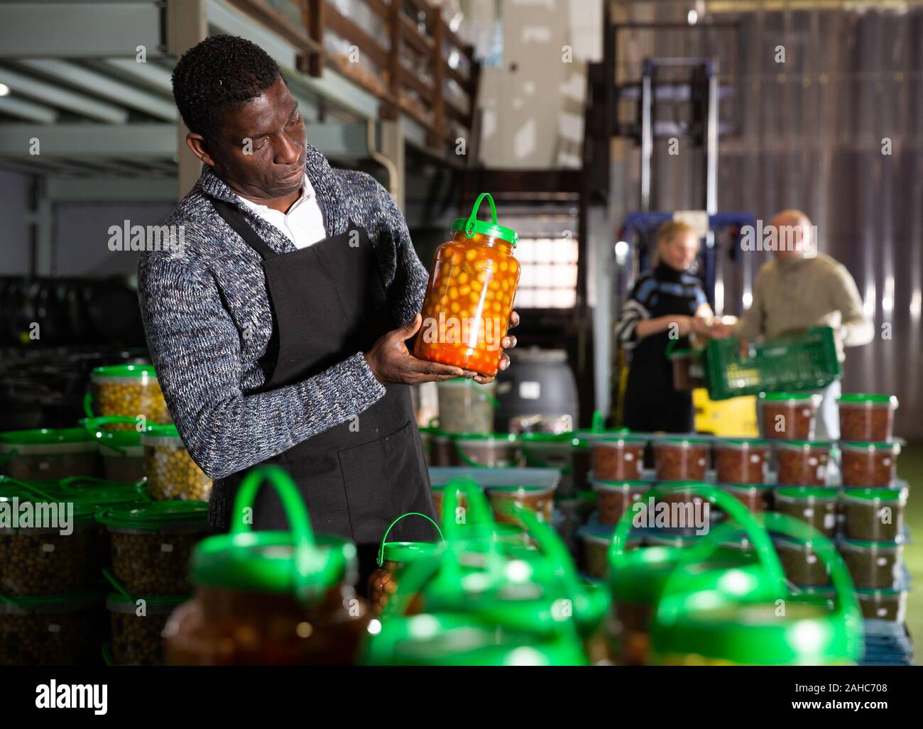 Afro-american male worker stocks plastic containers and cans with ...