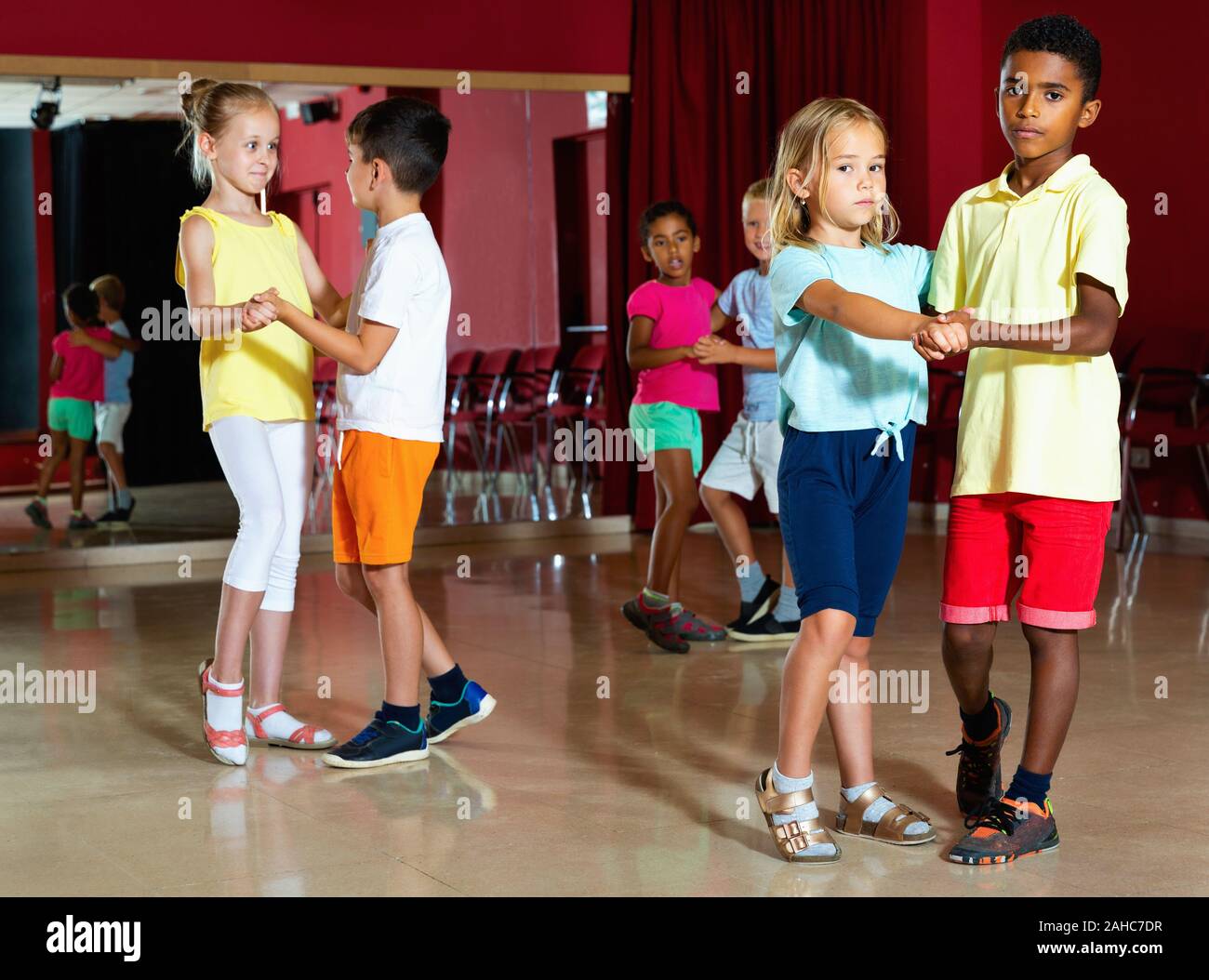 Group of glad cheerful positive childrens trying dancing with partner ...