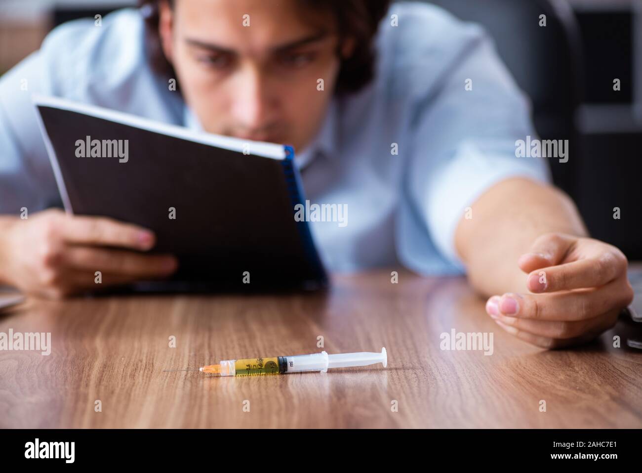 The young man having problems with narcotics at workplace Stock Photo ...