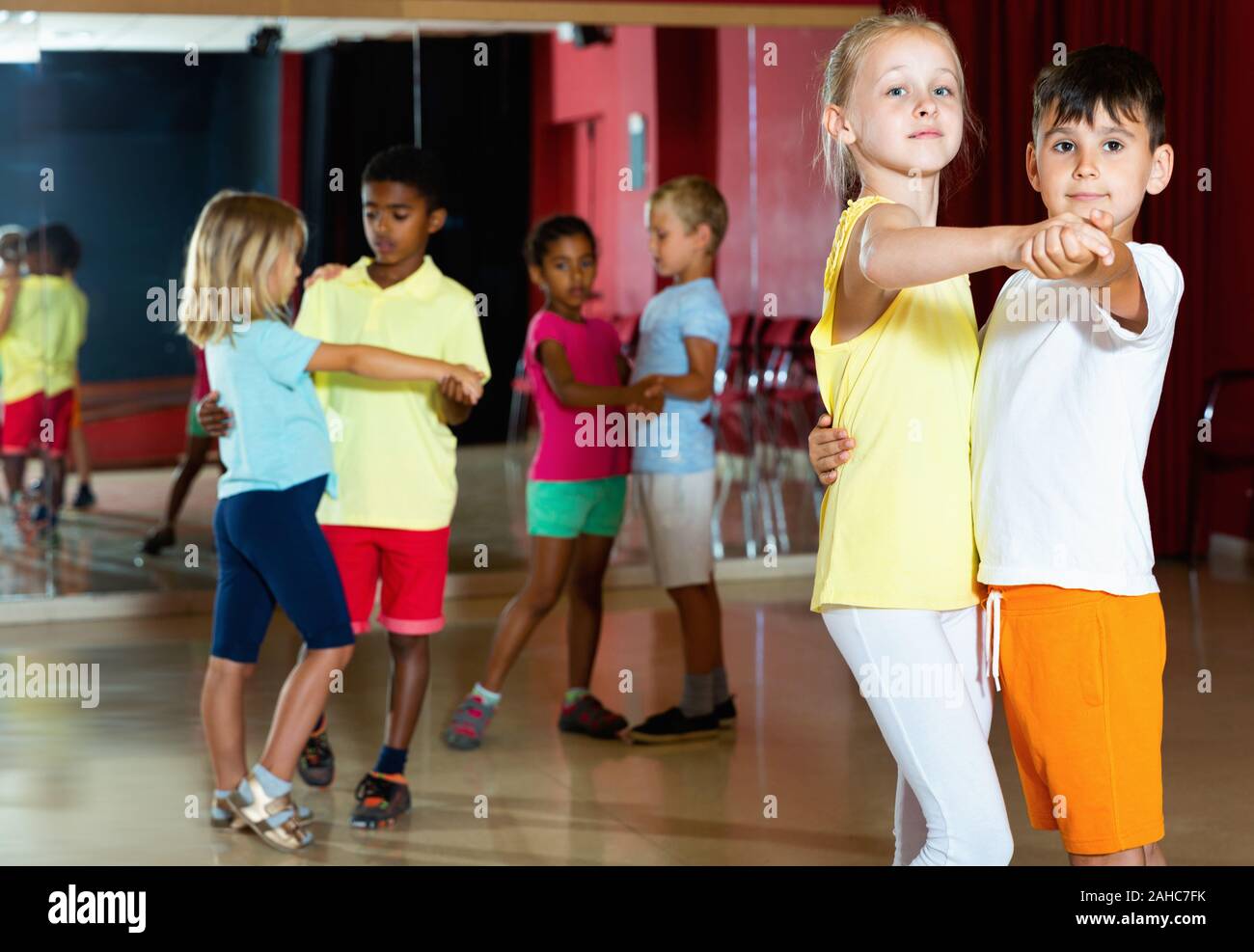 Group of glad positive childrens trying dancing with partner in ...