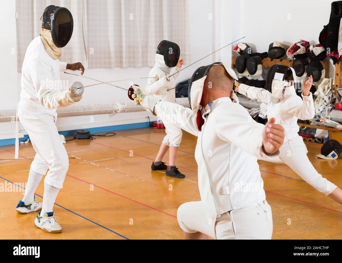 Mixed age group of athletes at fencing workout, training attack ...