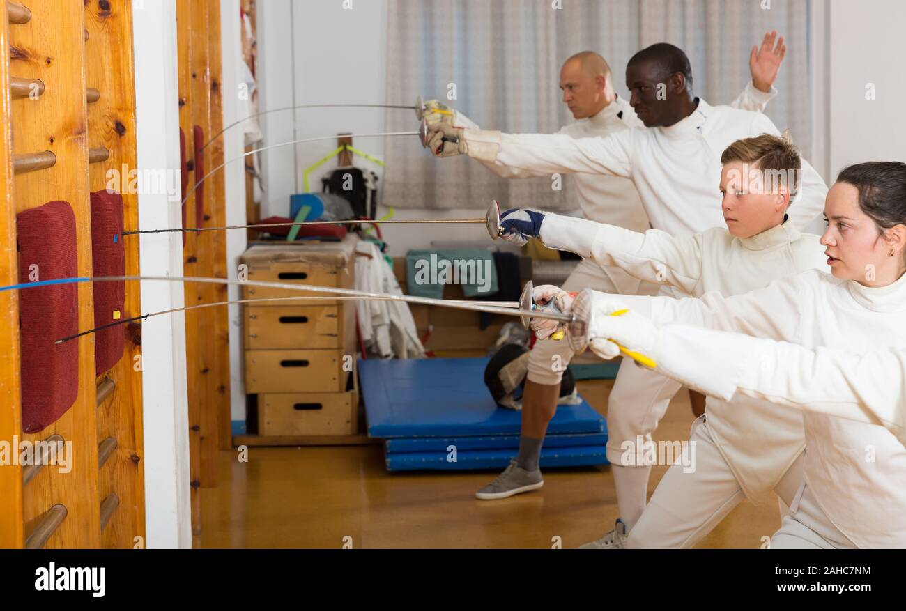 portrait of fencers exercising fencing technique on cushions in gym ...