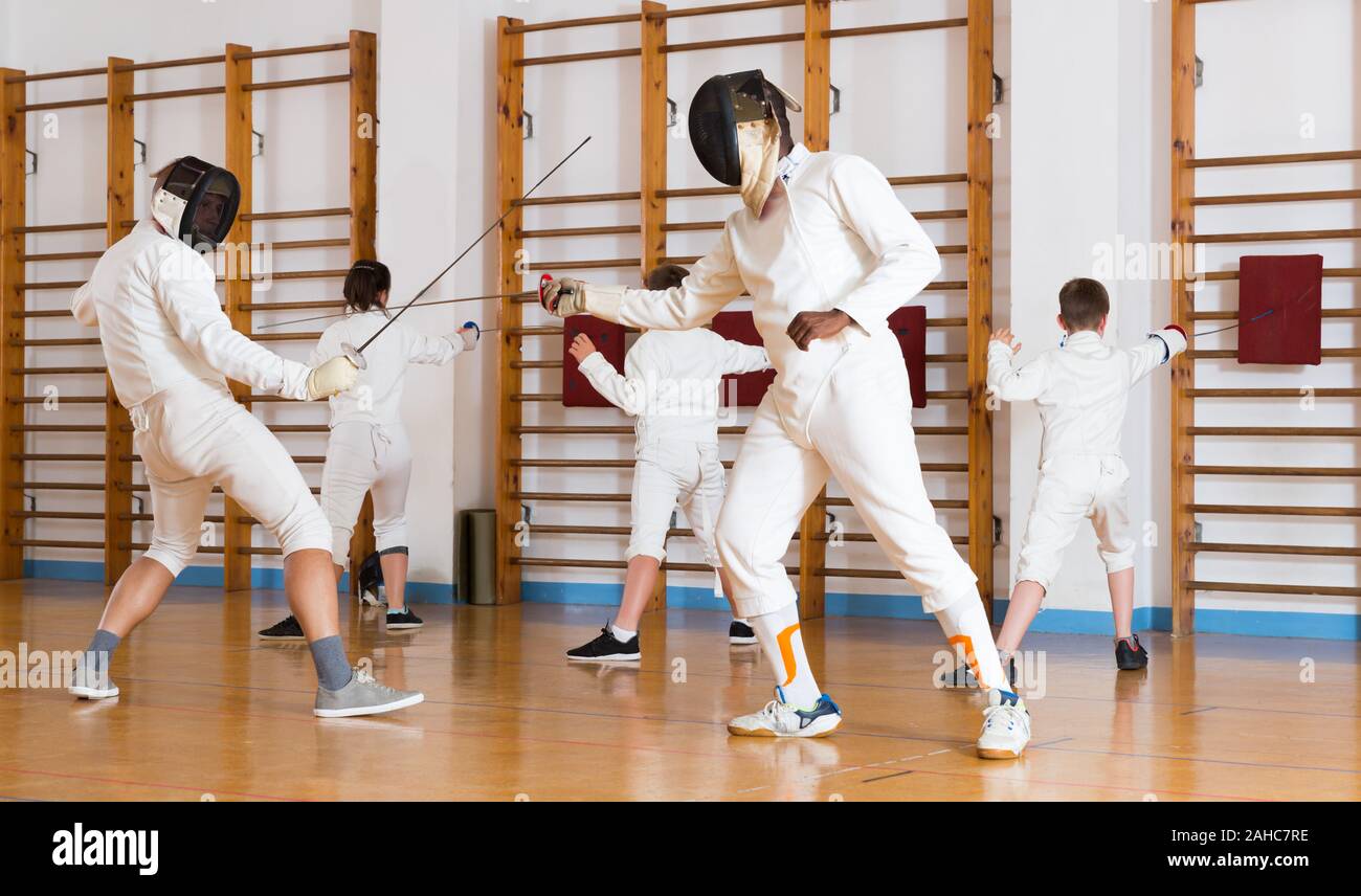 Smiling group practicing effective fencing techniques in sparring in ...