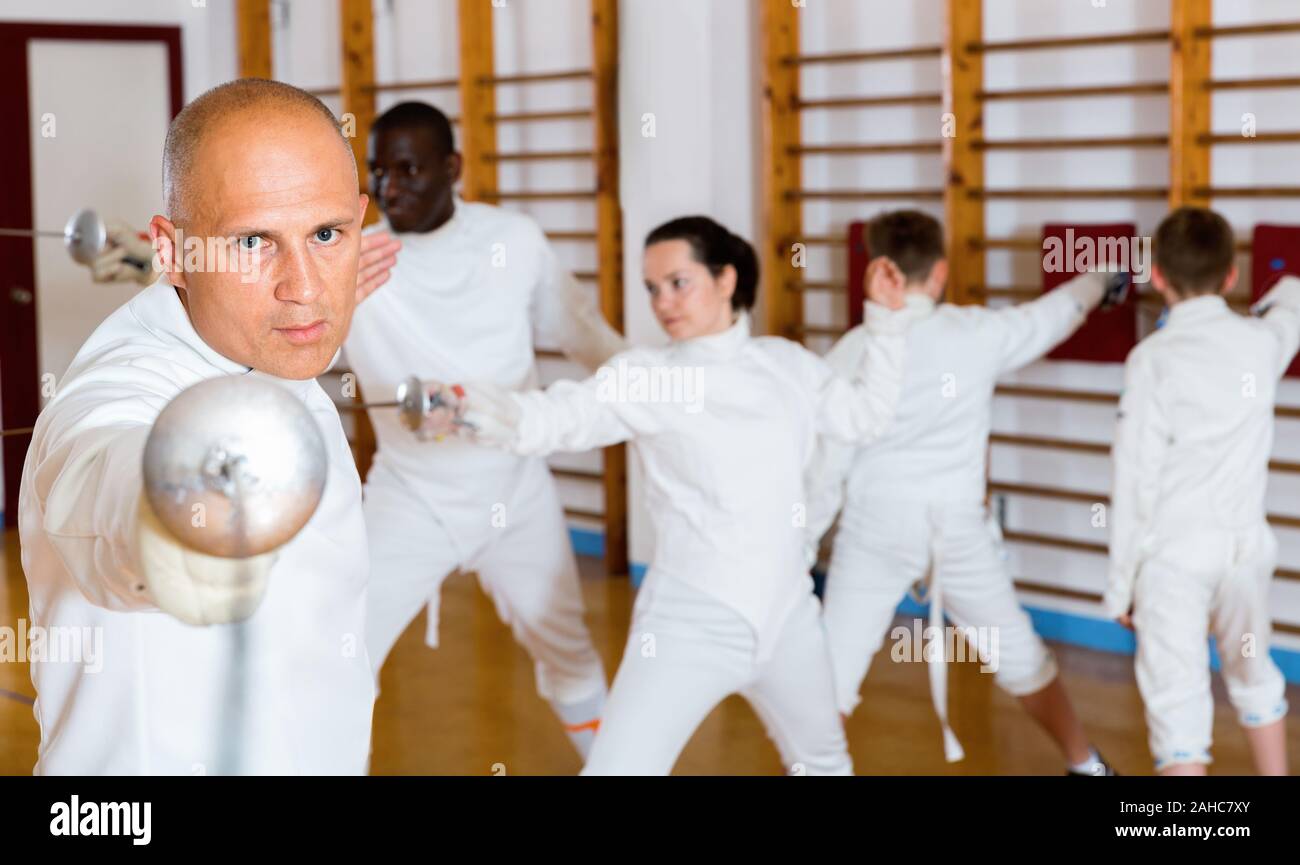 Adult cheerful positive man fencer practicing effective fencing ...