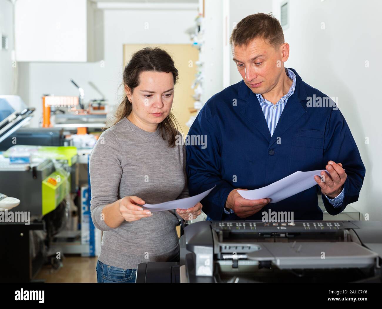 Female designer and print operator working together at the print ...