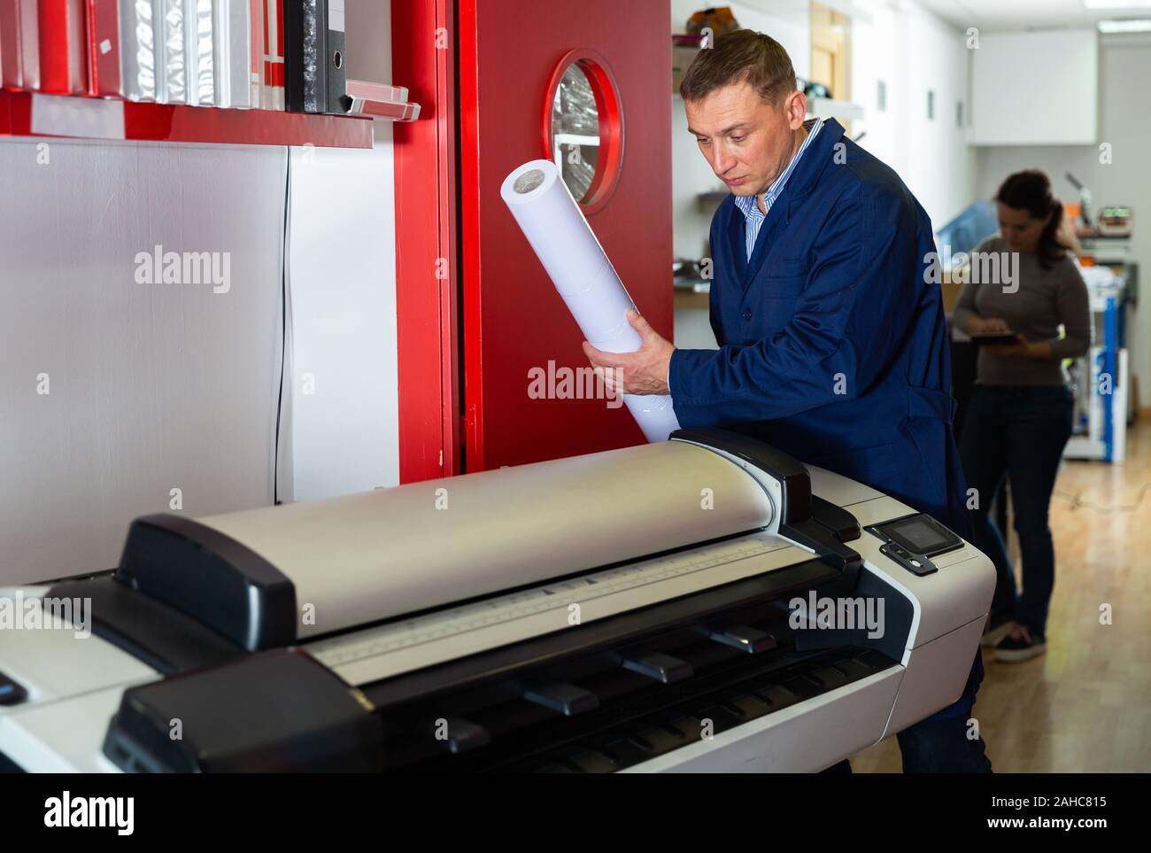 Repairman changes paper roll in plotter Stock Photo - Alamy