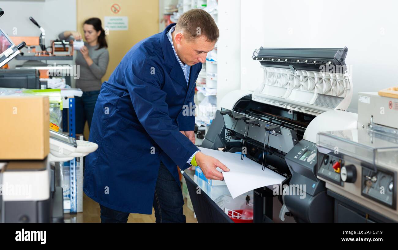 Worker loads new roll of paper into the plotter Stock Photo - Alamy