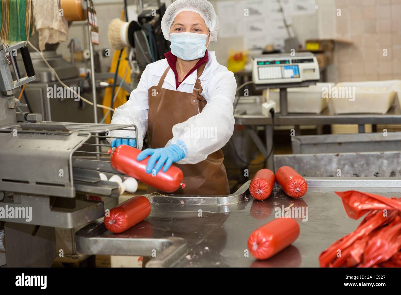 Female worker controlling conveyor of cooked sausages production on meat factory Stock Photo - Alamy