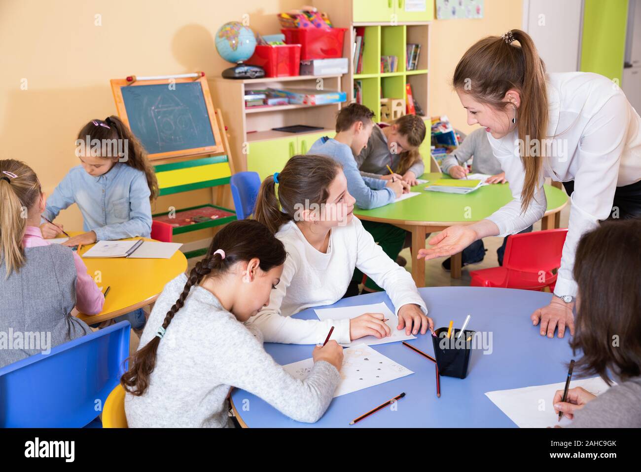 Group of diligent friendly smiling school kids with pens and notebooks ...