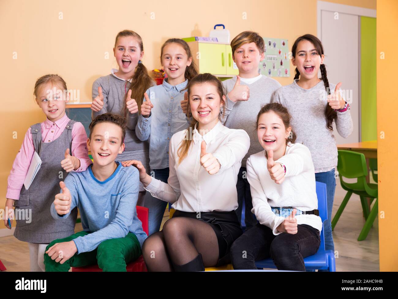 Cheerful group of pupils with female teacher posing together in ...