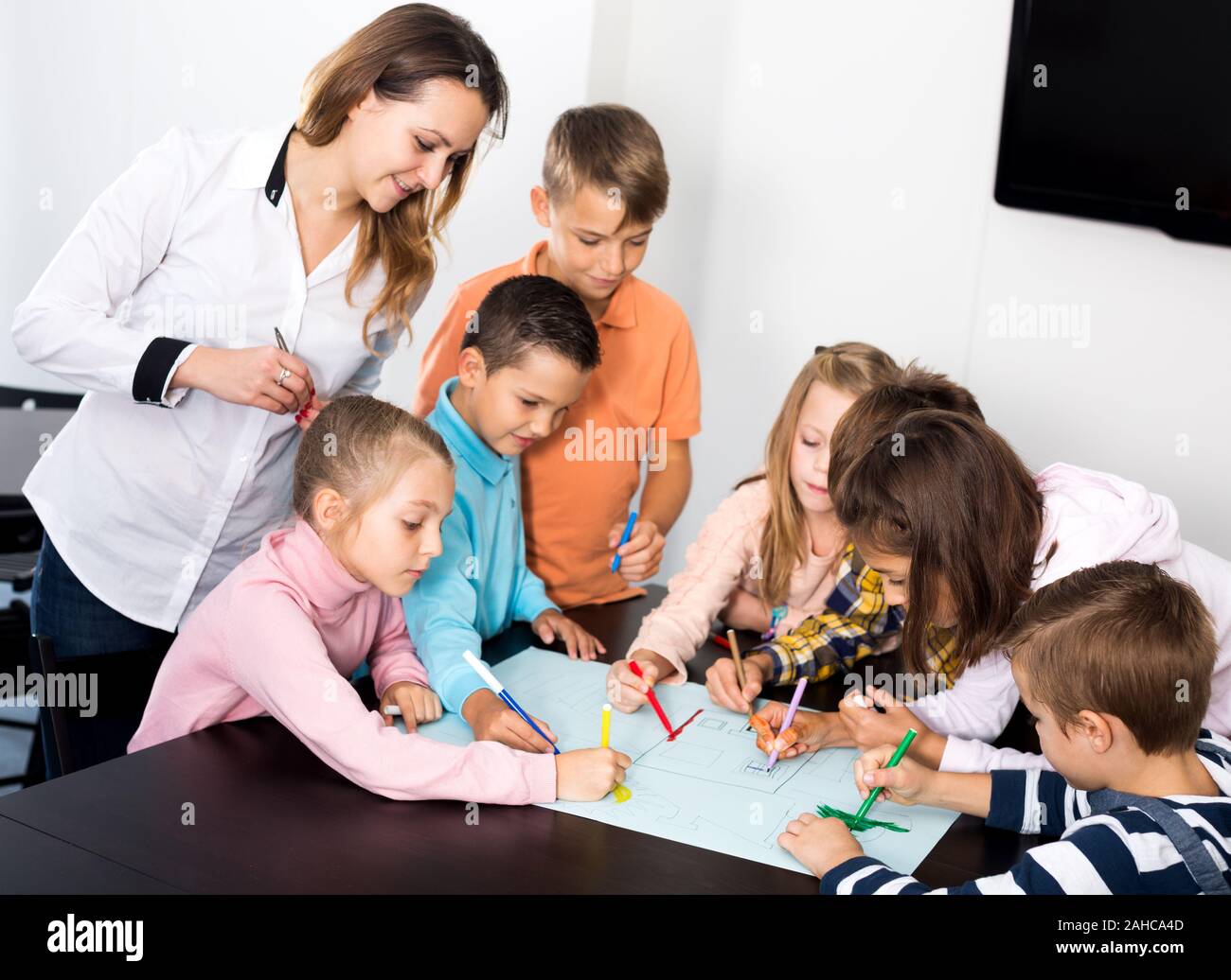 Happy team of elementary age children drawing on one sheet Stock Photo ...
