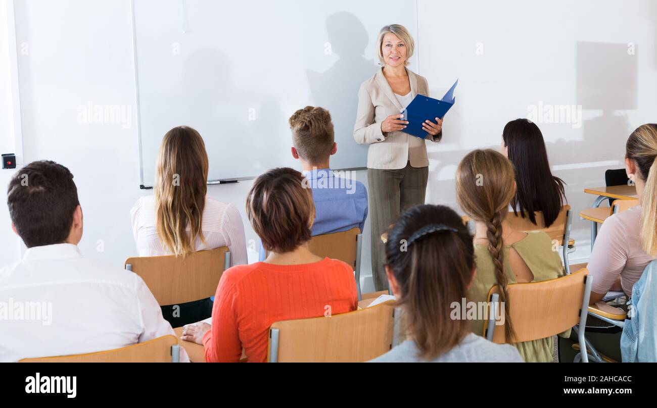 Mature female speaker giving presentation for students in lecture hall ...